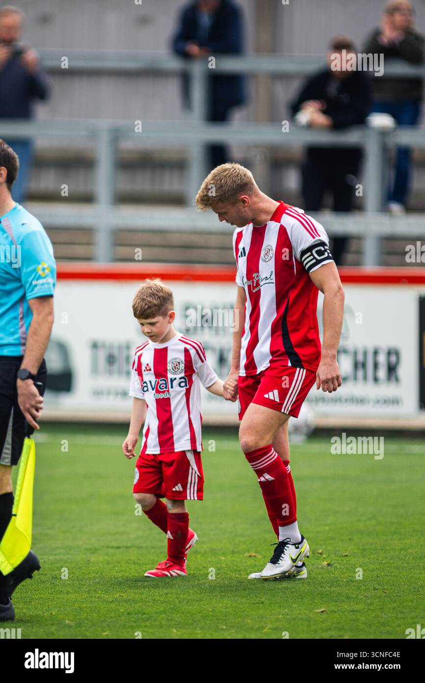 Brackley, UK. 20th Sep, 2025. Gareth Dean (6 Brackley Town) walks out with a mascot before the ...