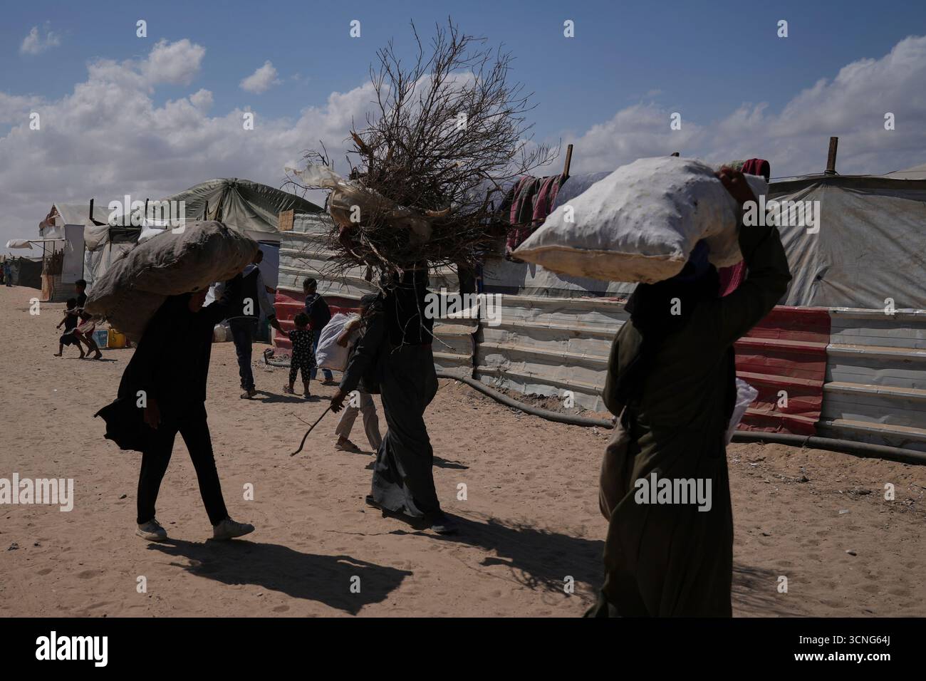 Displaced Palestinians walks through a tent camp in Muwasi, an area ...