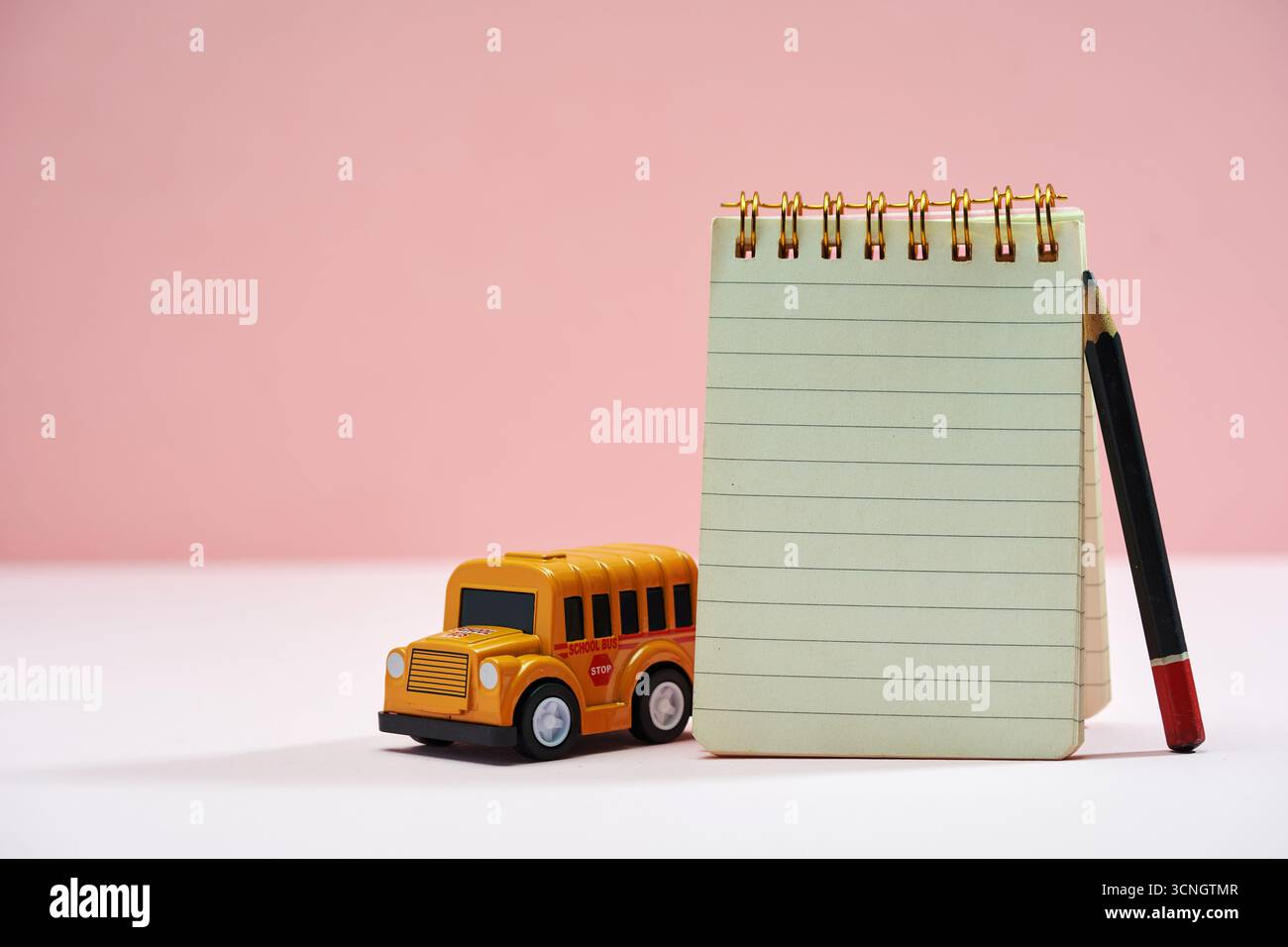 toy school bus and blank note pad against pink background Stock Photo ...