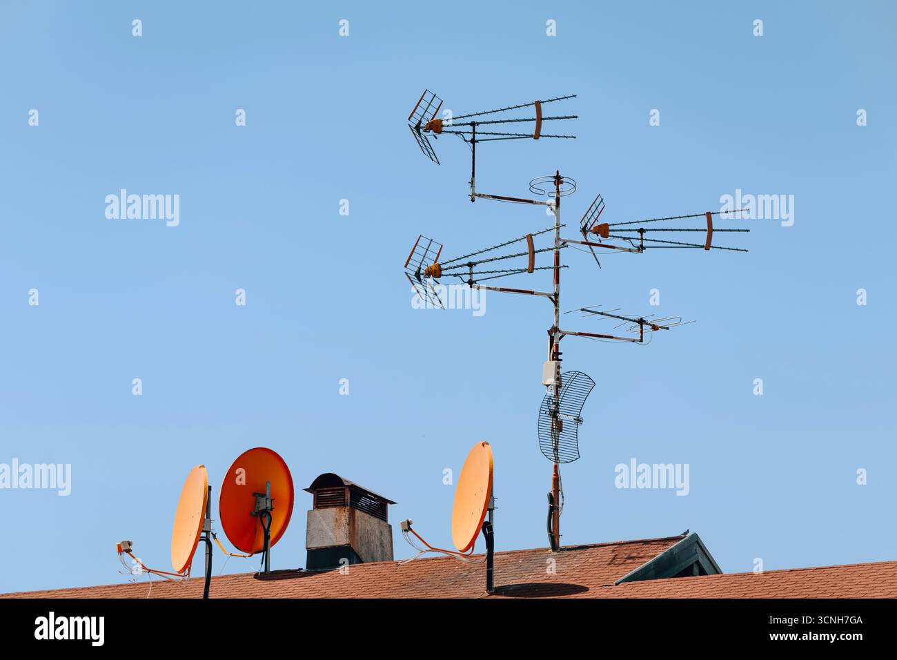 Multiple television antennas and satellite dishes are installed on a ...