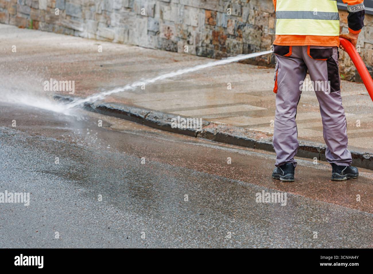 Sanitary worker using a pressurized water jet to clean the sidewalk ...