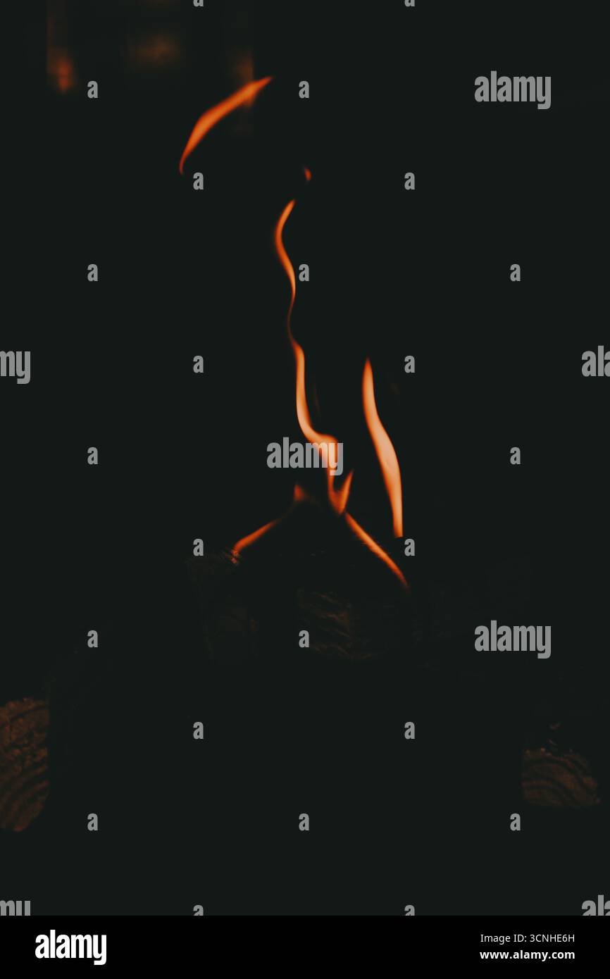 Dark minimalistic shot of orange flames rising in the darkness ...