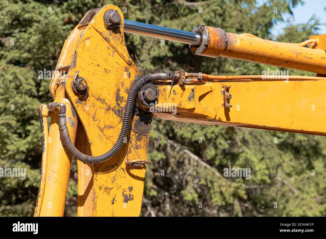 Yellow excavator arm featuring a hydraulic piston and cylinder, showing ...