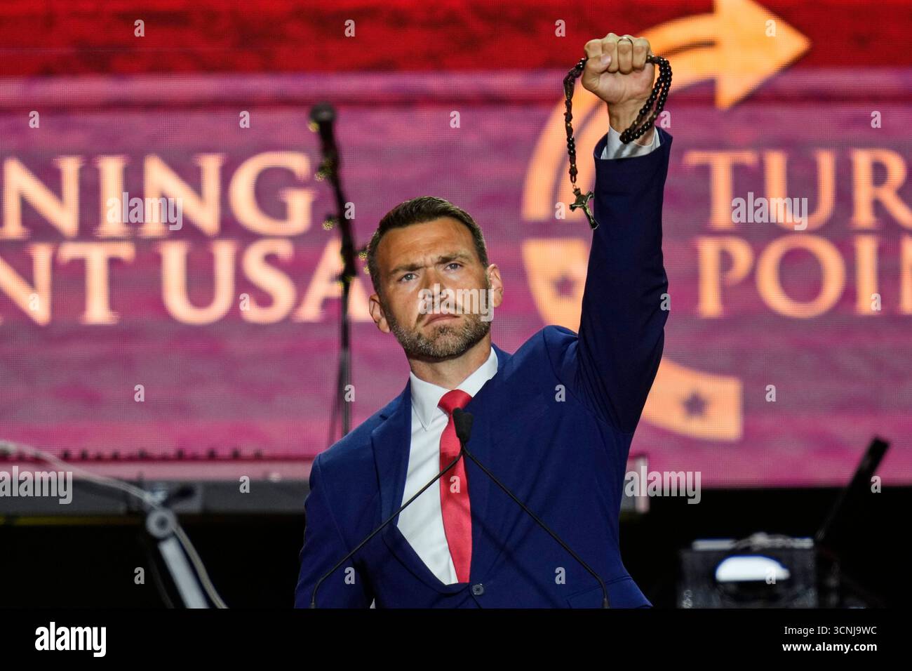 Jack Posobiec holds up a rosary as he speaks at a memorial for ...