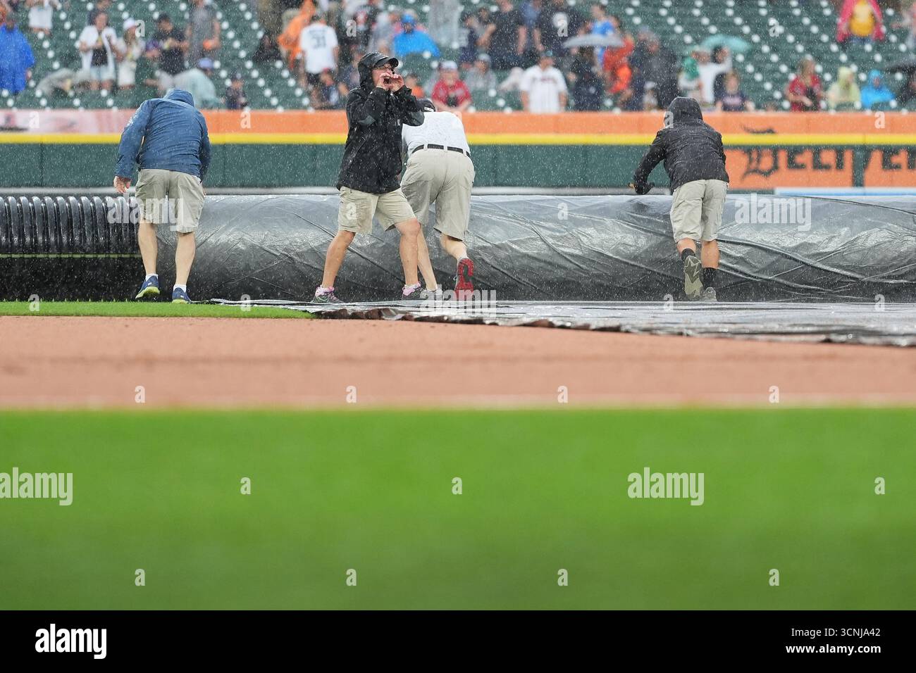 Groundskeepers roll out a tarp during a weather delay during the ...