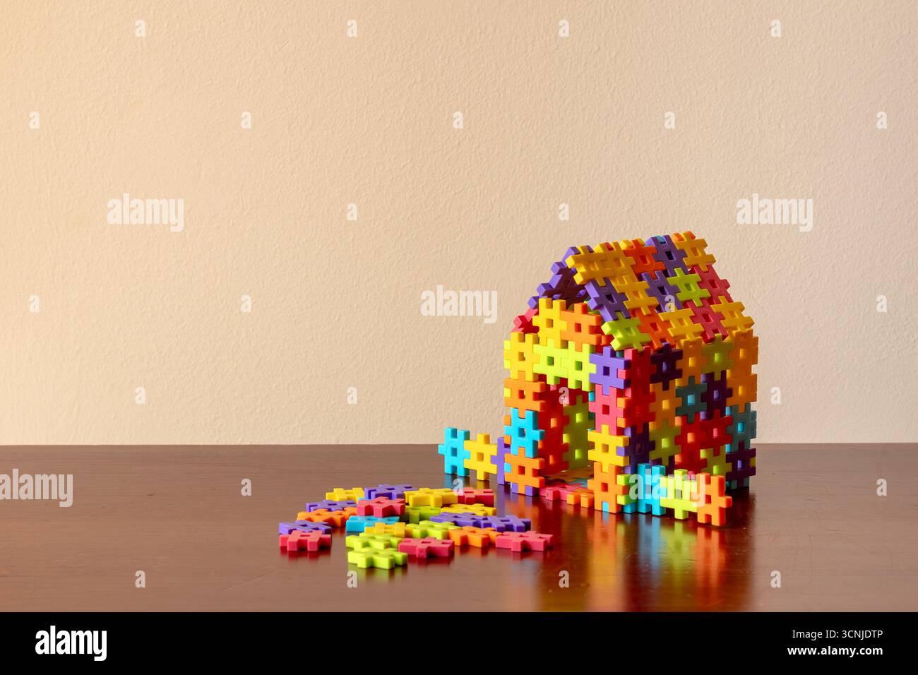 Colorful interlocking plastic puzzle pieces forming a small house ...