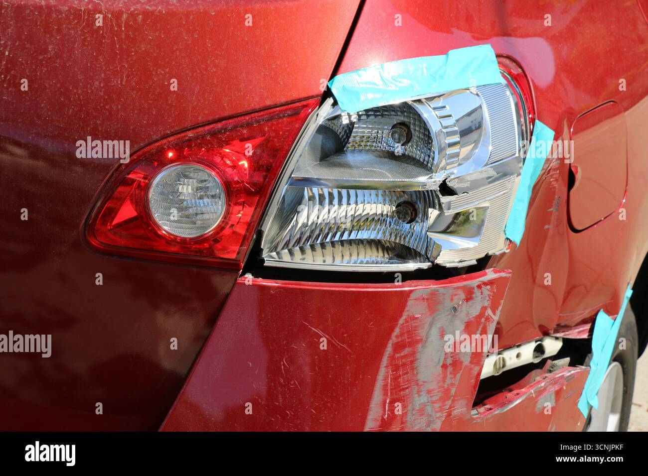 Damage to the rear of a red car. The owner has used blue tape to hold ...