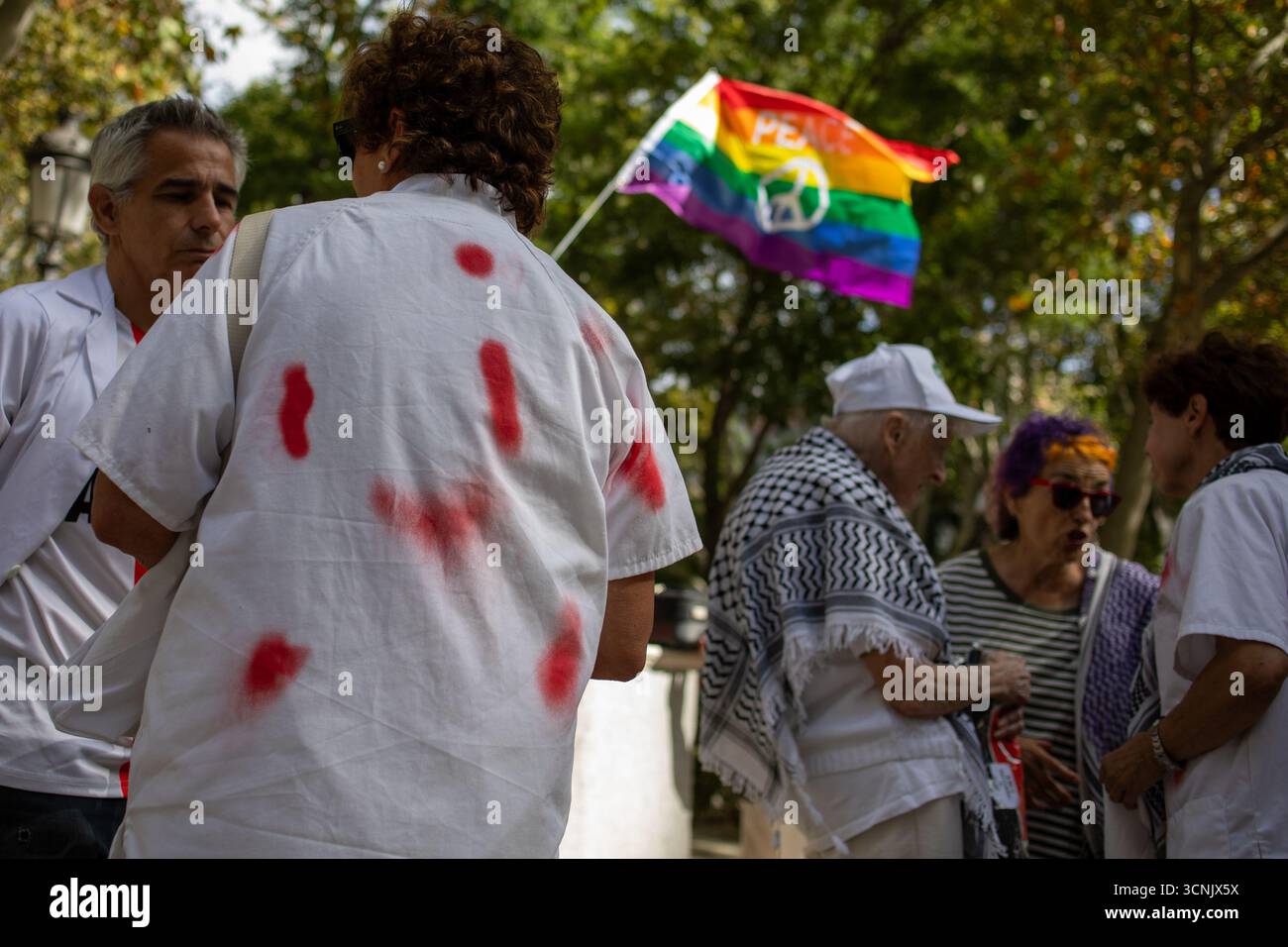 Protesters wearing white coats with red stains resembling bloodstains ...
