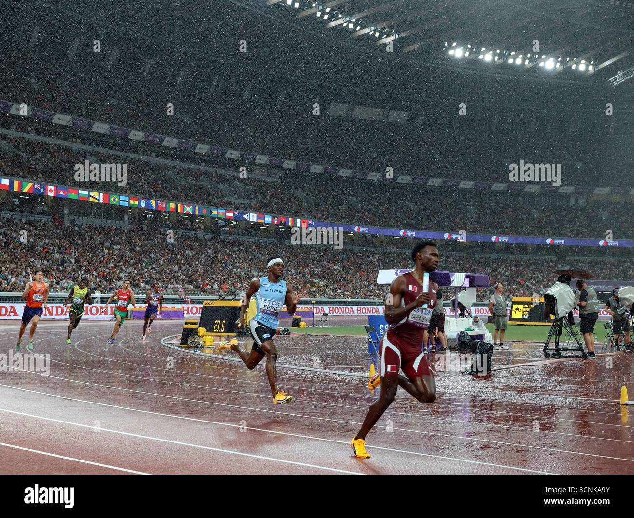 Athletes compete in an intense rainfall in the men's 4x400 meters relay ...