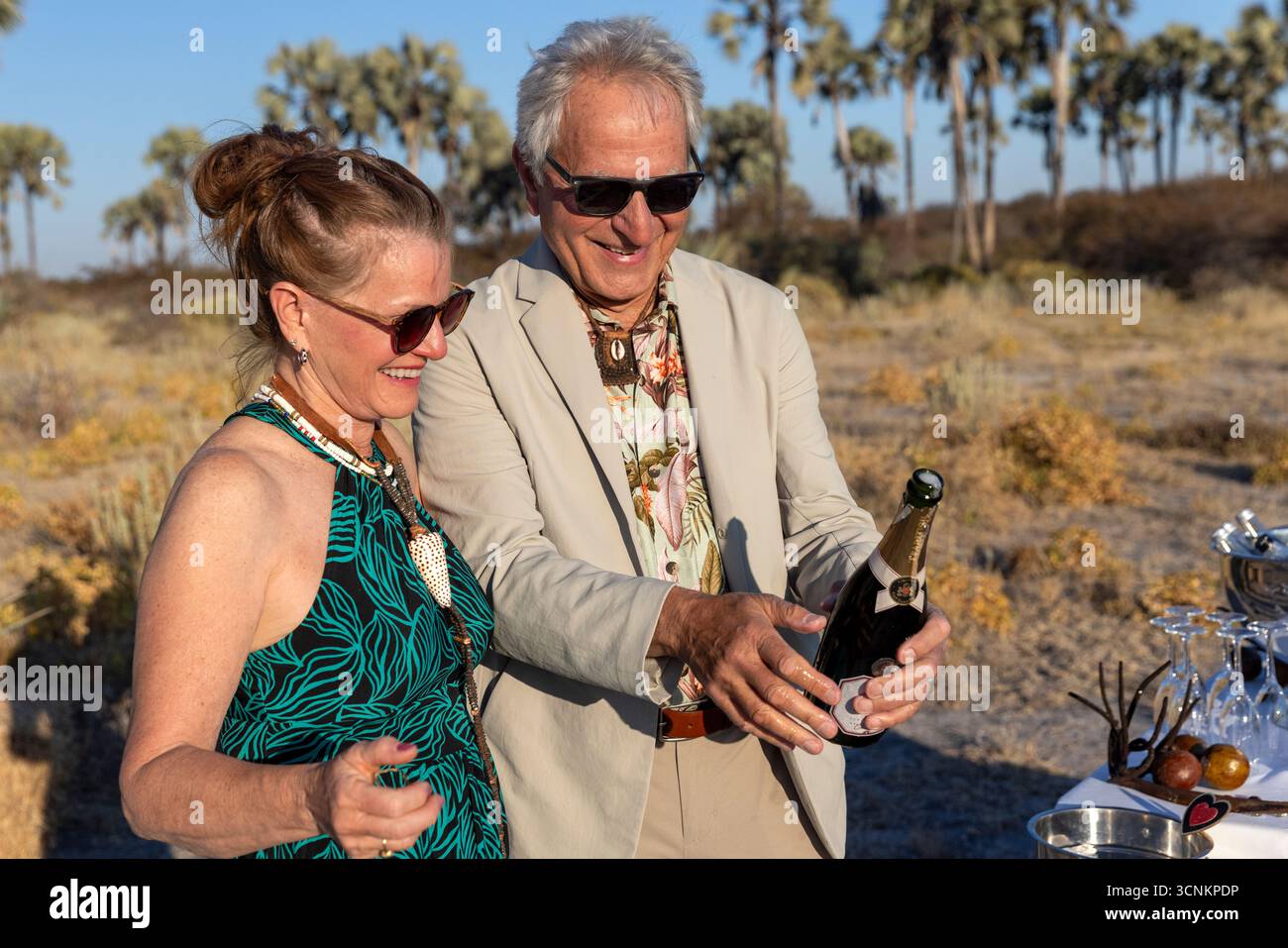 Wedding couple opening champagne at outdoor wedding ceremony in the ...