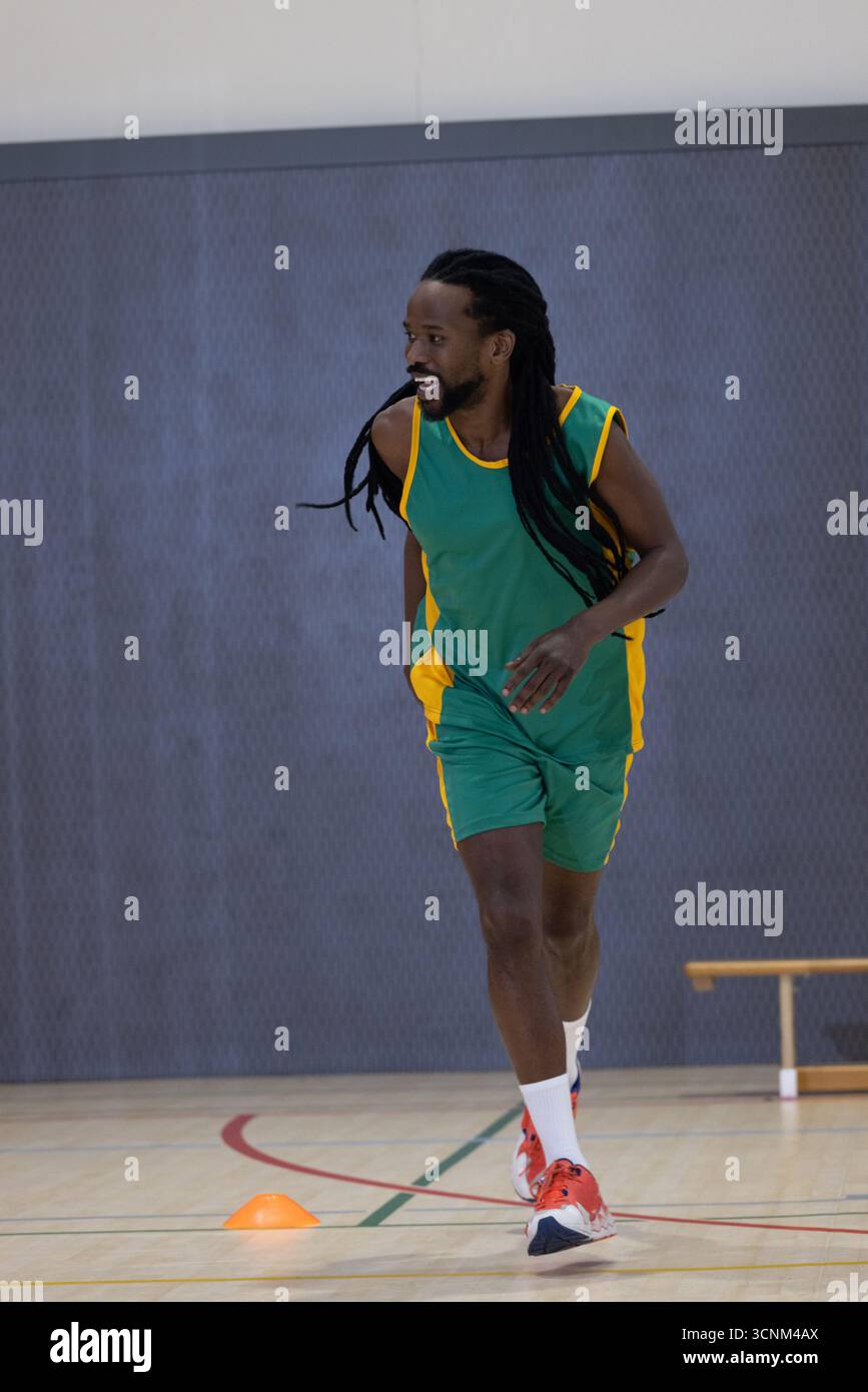 African american man running across basketball court in green ...