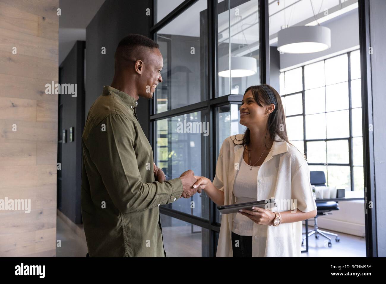 Diverse coworkers shaking hands wearing business casual attire holding ...