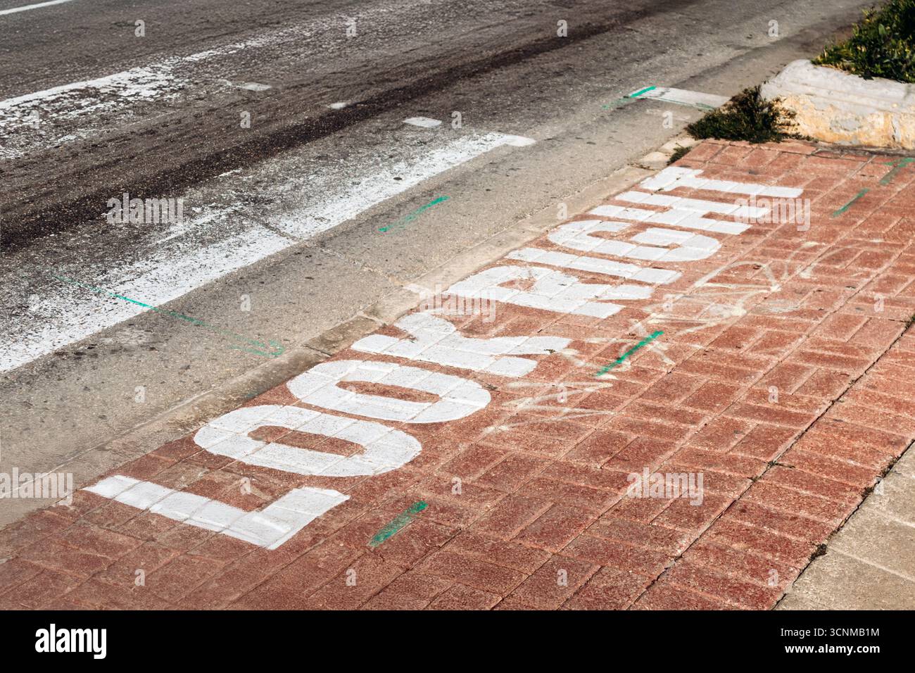 White painted words “LOOK RIGHT” on a brick sidewalk at a pedestrian ...