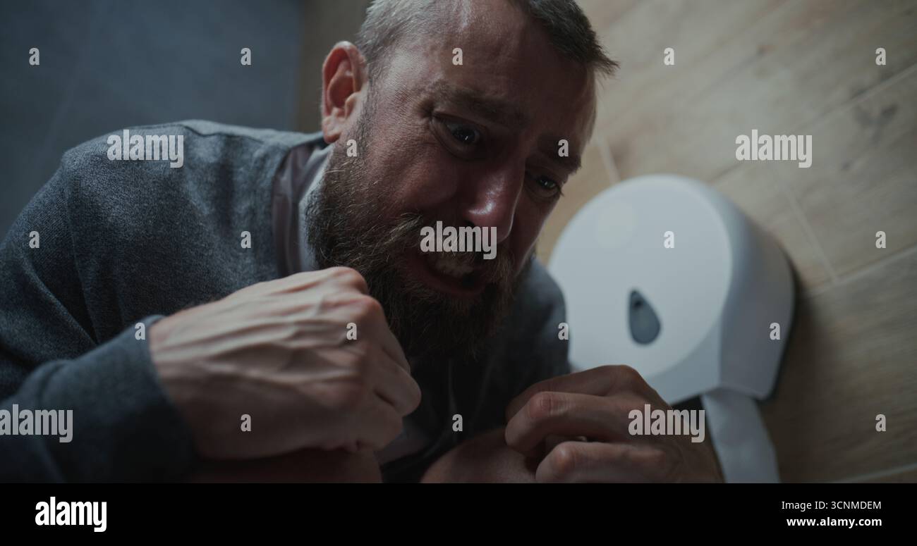 Man with Tense Facial Expression Sitting on Toilet, Suffering from ...