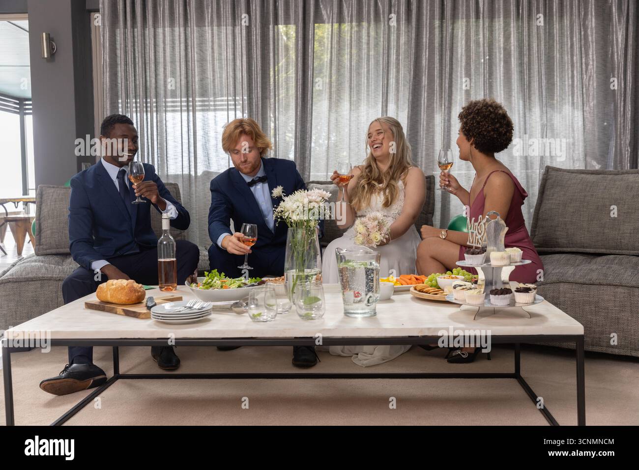 Diverse wedding party in formal wear eating appetizers, holding wine ...