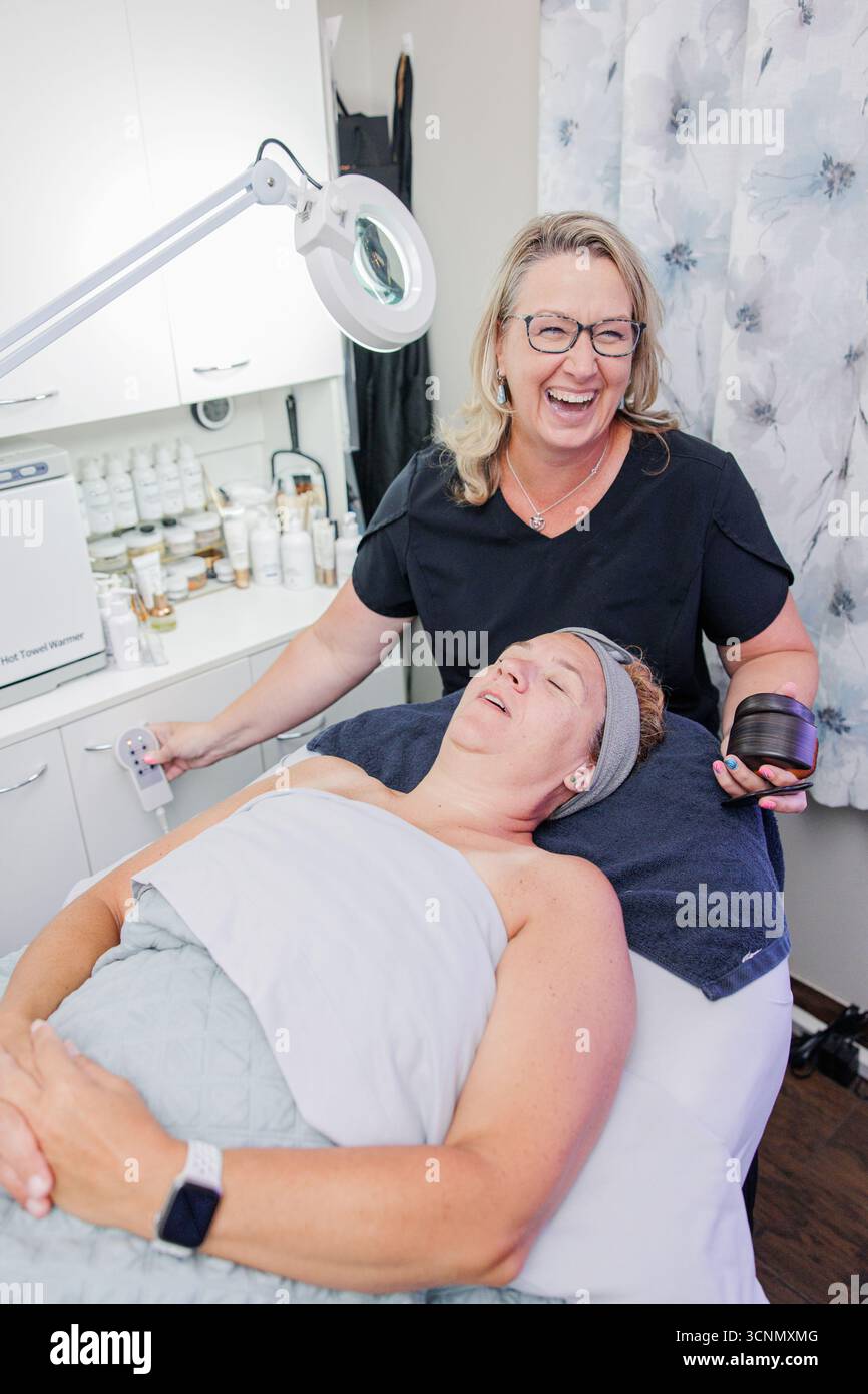 Esthetician laughing while performing a facial treatment Stock Photo ...