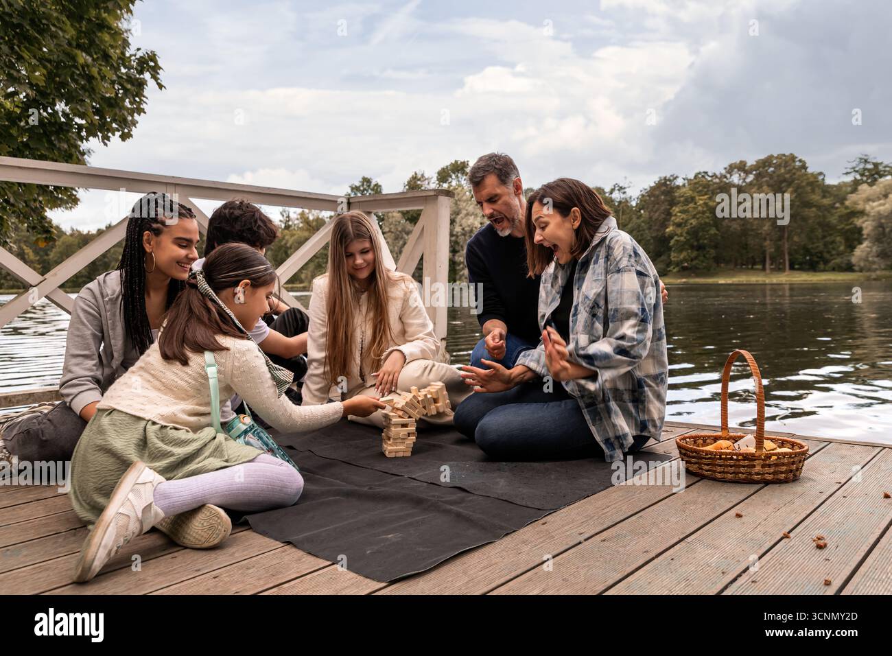 Multiethnic family group playing Jenga on lake pier Stock Photo - Alamy