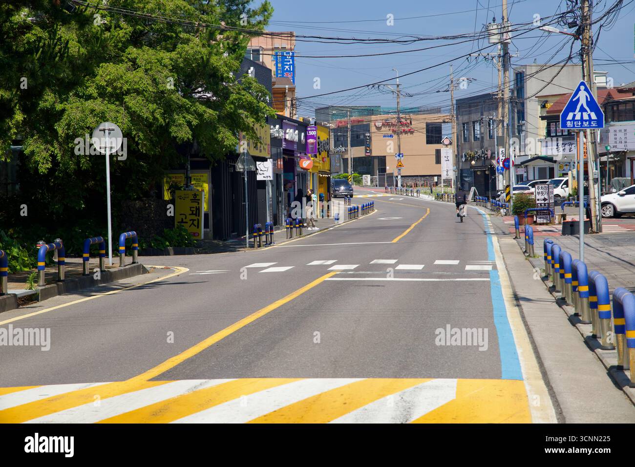 A gently curving main street near Pyoseon Port shows shops, poles, and ...