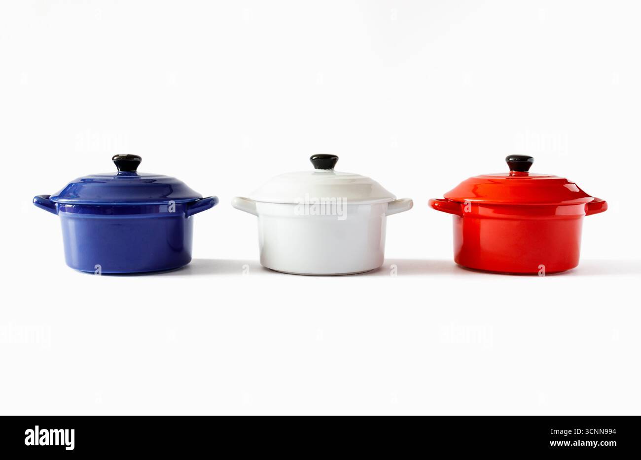Concept image of three mini casseroles in blue, white and red on a ...