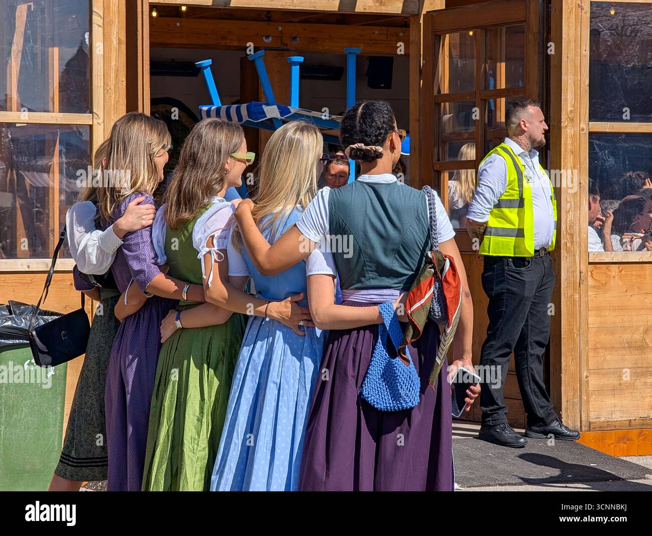 Women dressed in traditional Dirndl stand together outside a beer tent ...