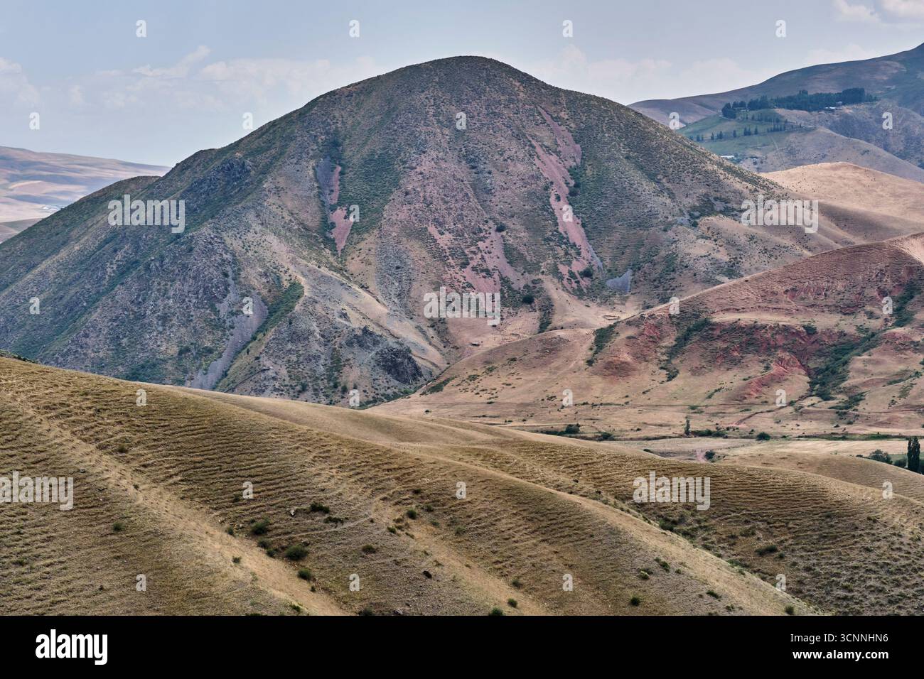 Dry mountain scene with rugged slopes, sparse vegetation, and rolling ...