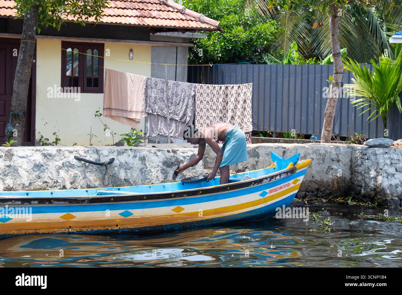 Alleppey backwaters in India, Alappuzha man painting boat on waterway ...