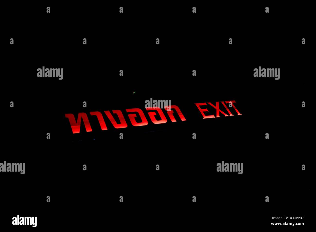 Red exit sign, bilingual sign in Thai and English, in cinema theatre ...
