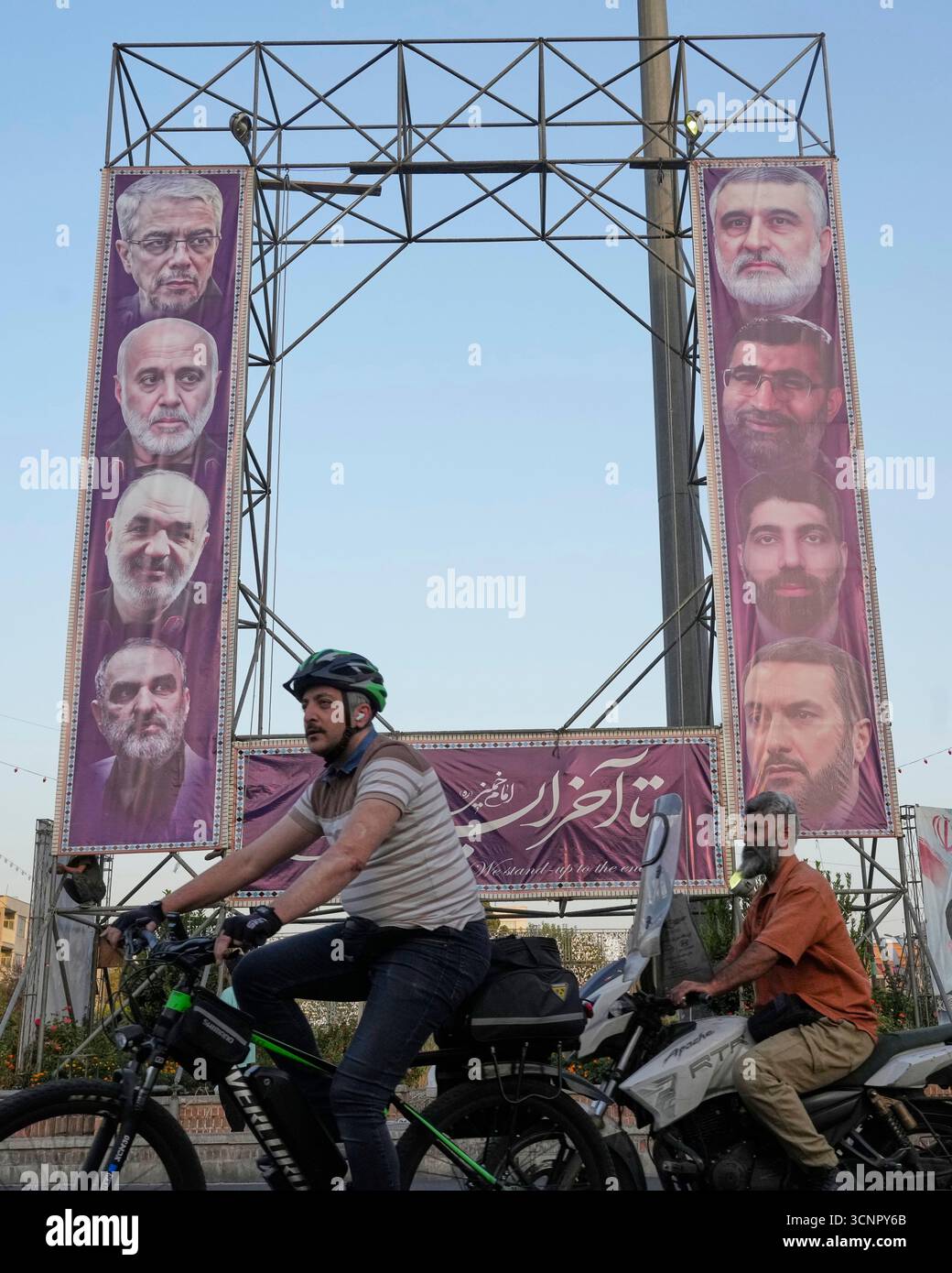 People drive in front of banners showing portraits of the late Iranian ...
