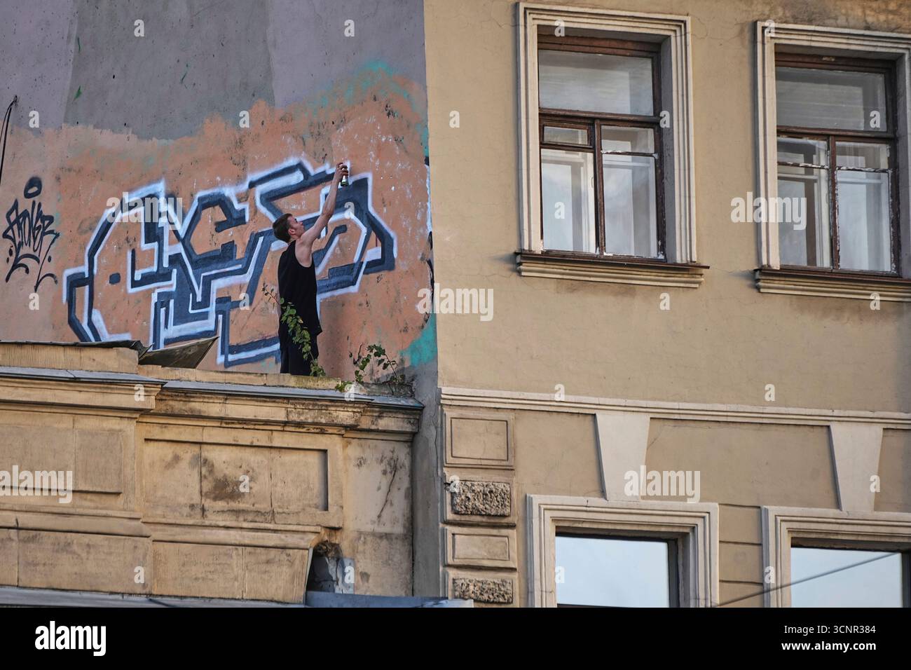 A man draws graffiti on the wall of an apartment building in central St ...