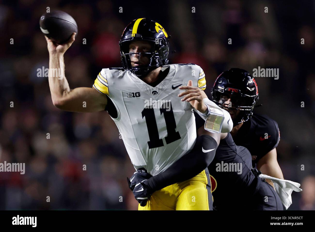 Iowa quarterback Mark Gronowski (11) looks to pass the ball while being ...
