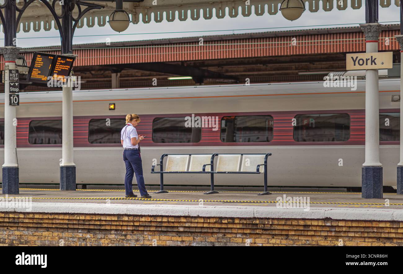 A crew member checks her phone standing on a historic railway station ...