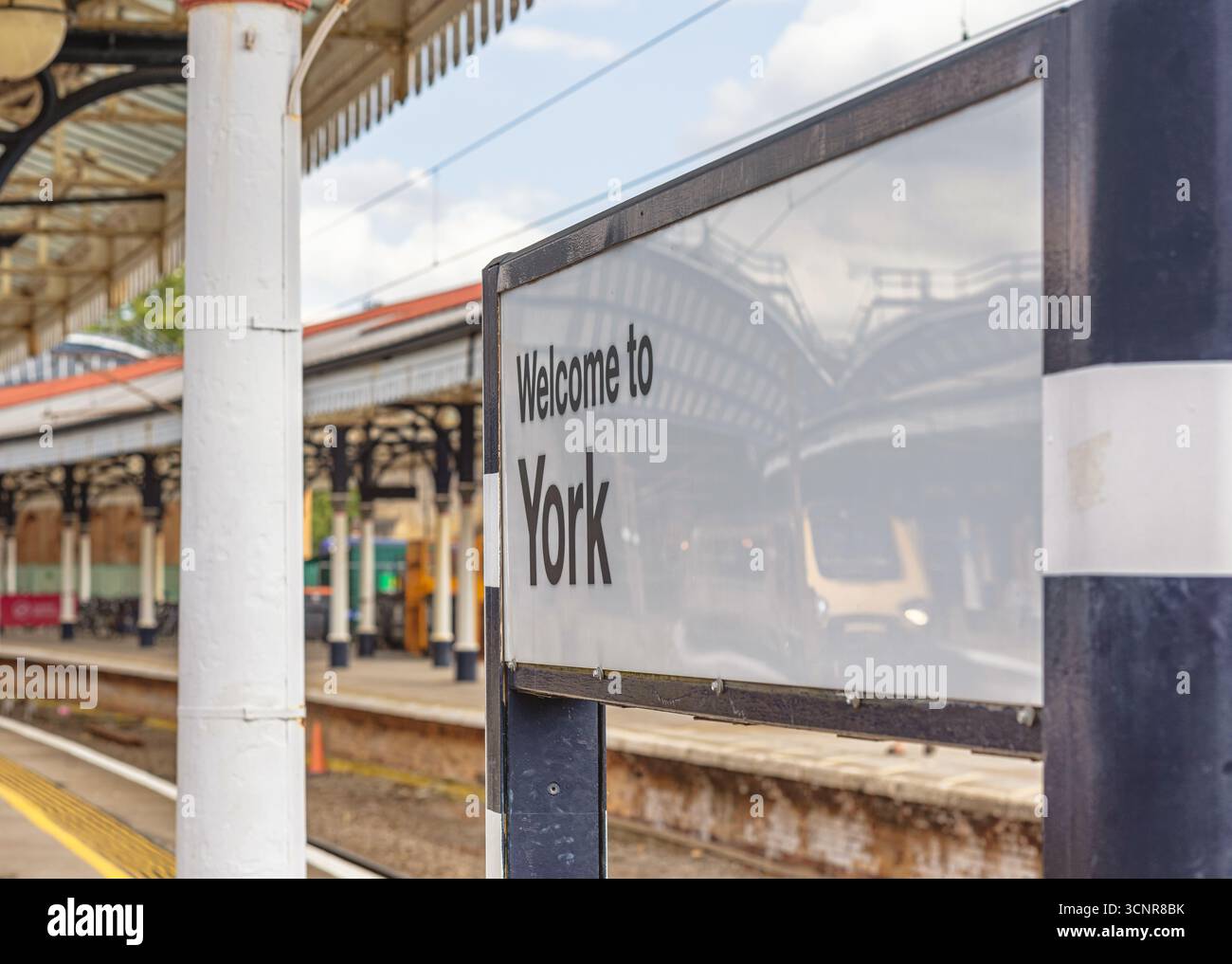 A railway station welcome sign with a reflection of a locomotive and ...