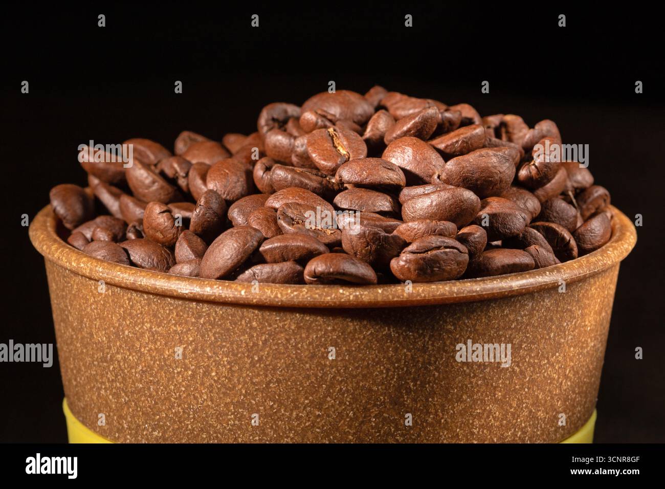 This image captures a plastic cup brimming with aromatic coffee beans ...