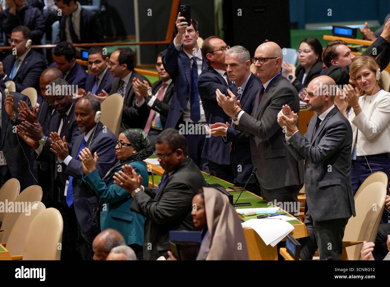 Delegates applaud after French President Emmanuel Macron announced ...
