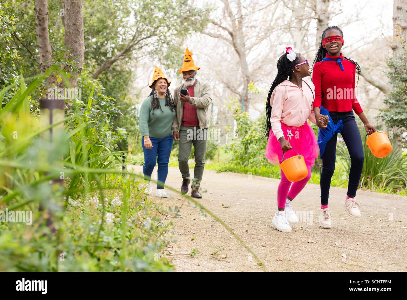 Diverse family walking on path, kids holding orange buckets and man ...