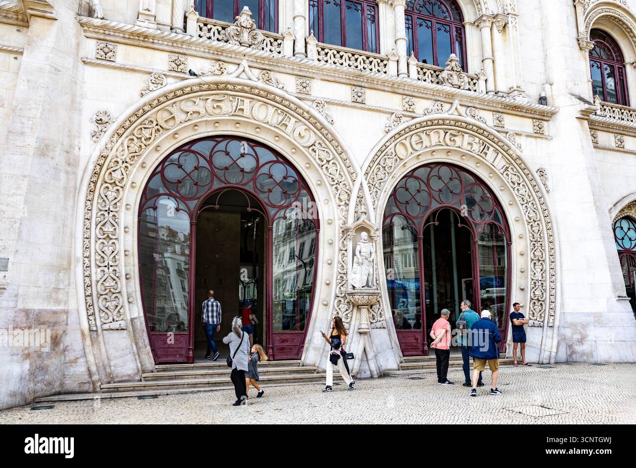People in front of the Neo-Manueline style facade of Rossio railway ...