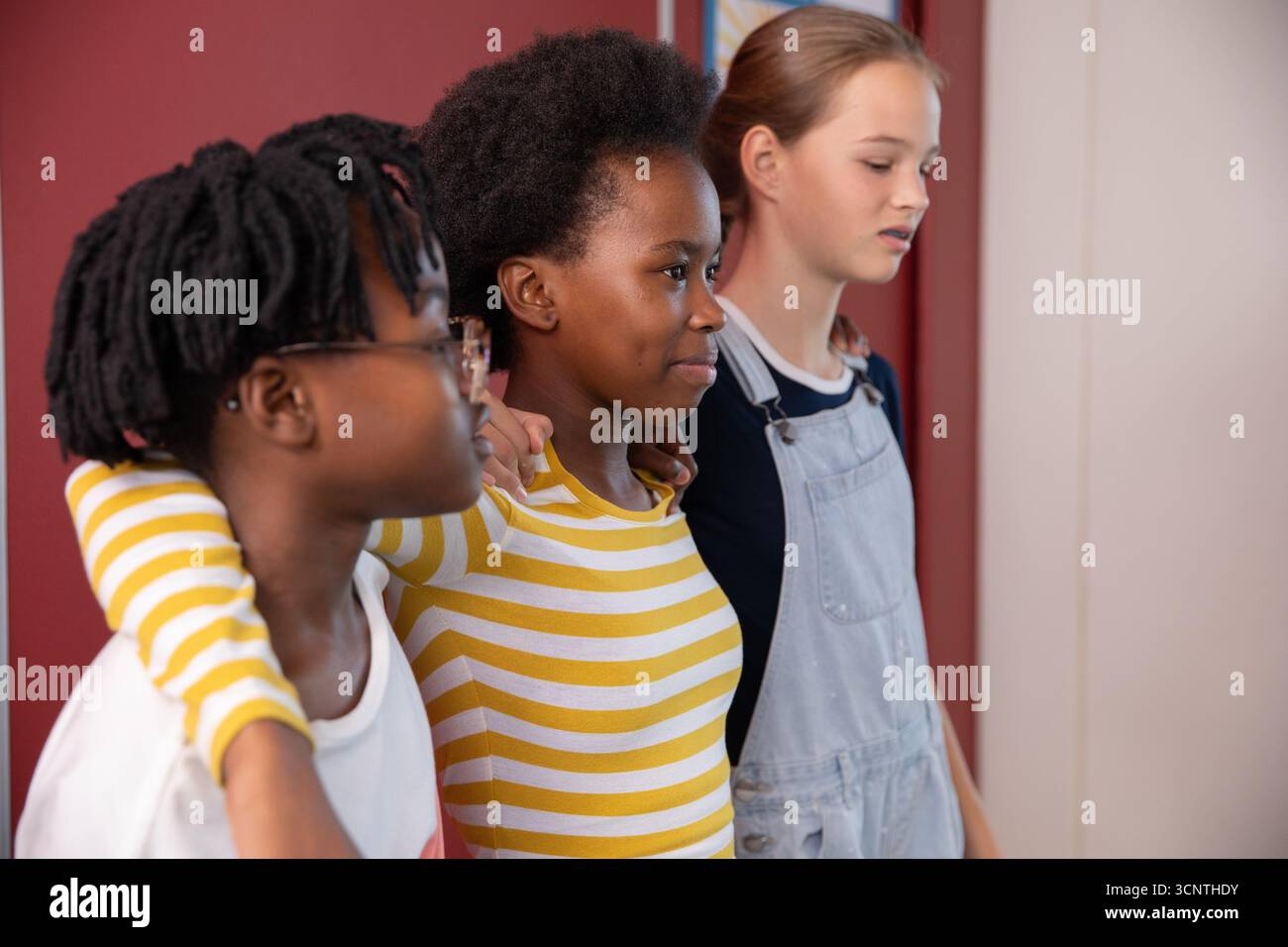 Diverse children friends linking arms around shoulders in classroom ...
