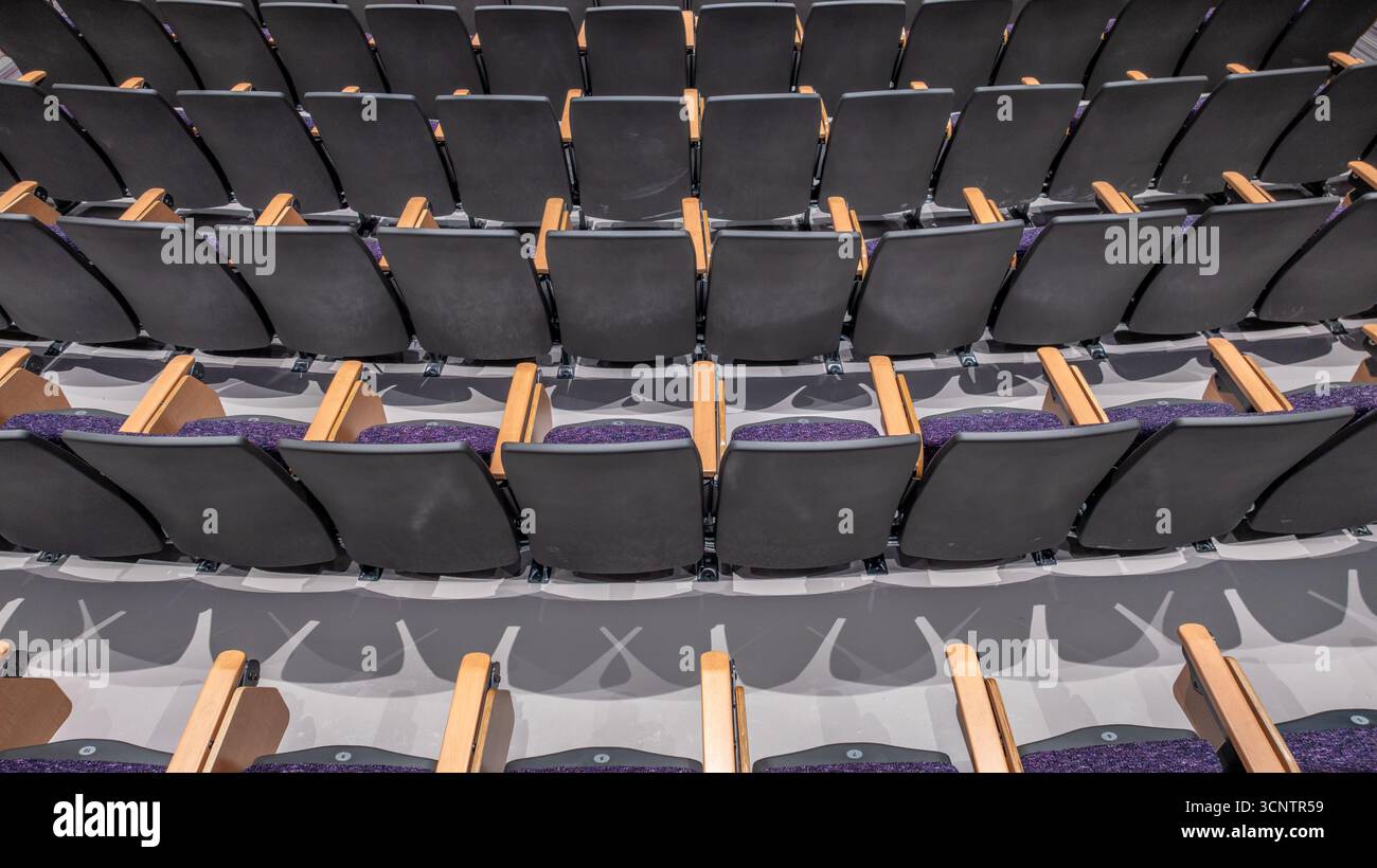 Purple padded auditorium seats, chairs with gray concrete floor, in an ...