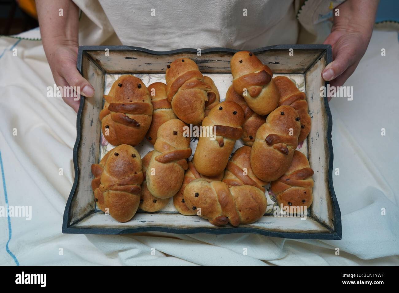 A person holds a rustic wooden tray with traditional "Lazarakia" sweet ...