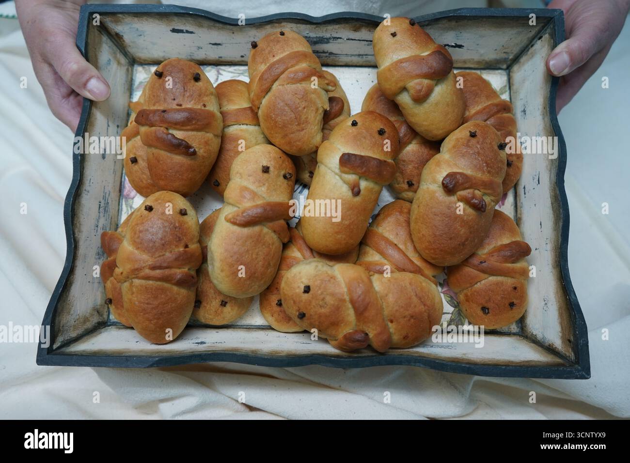 A person holds a rustic wooden tray with traditional "Lazarakia" sweet ...