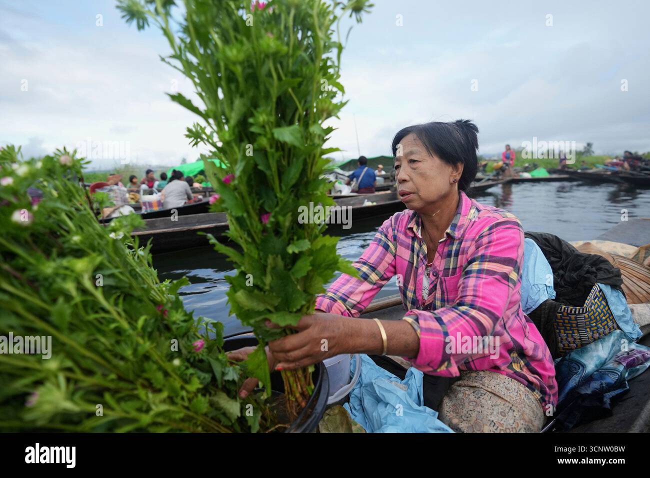 Vendor selling flowers wait for customers at a local floating bazaar ...