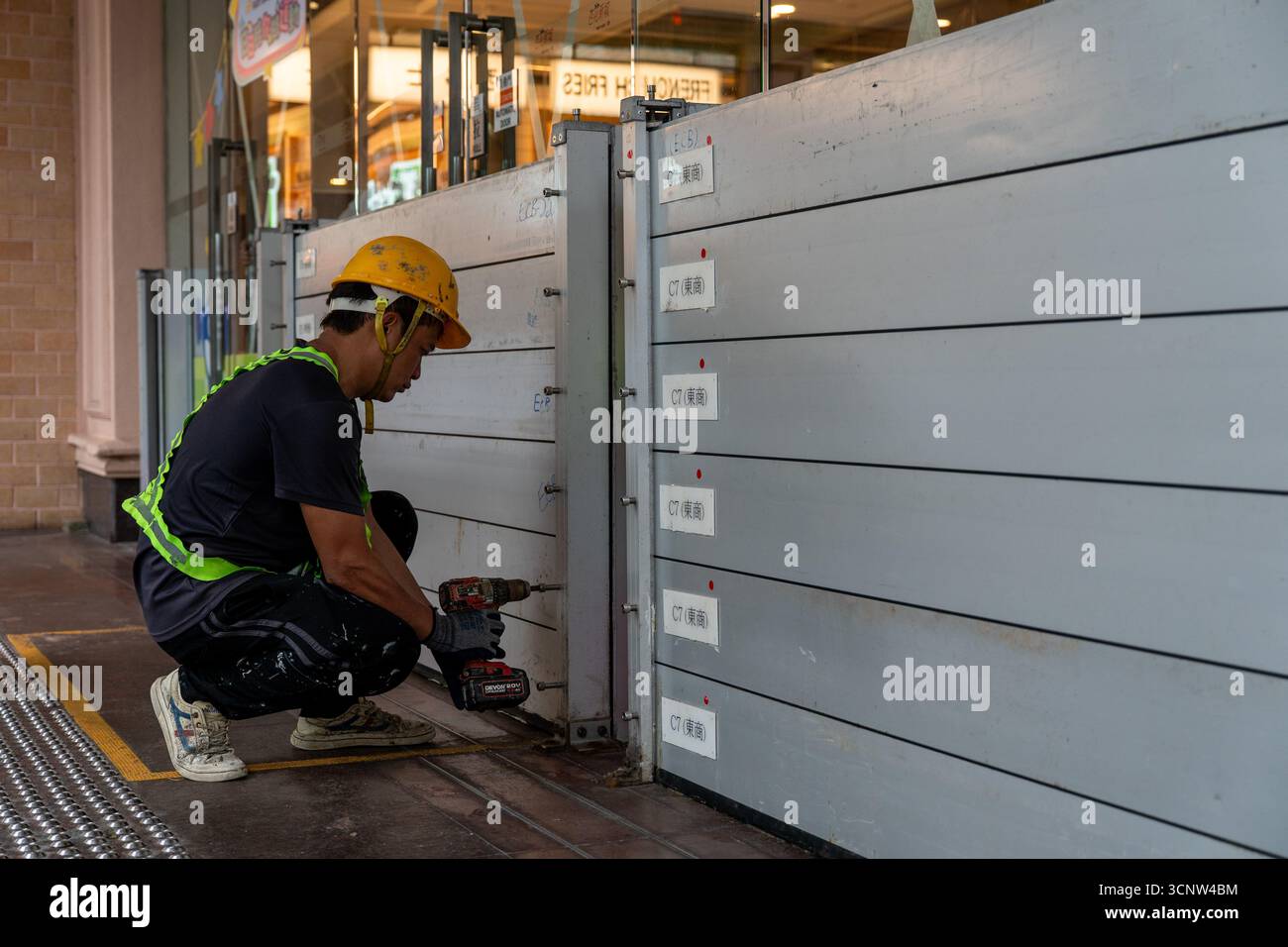 Workers installing water barricaders in front of glass doors to prepare ...