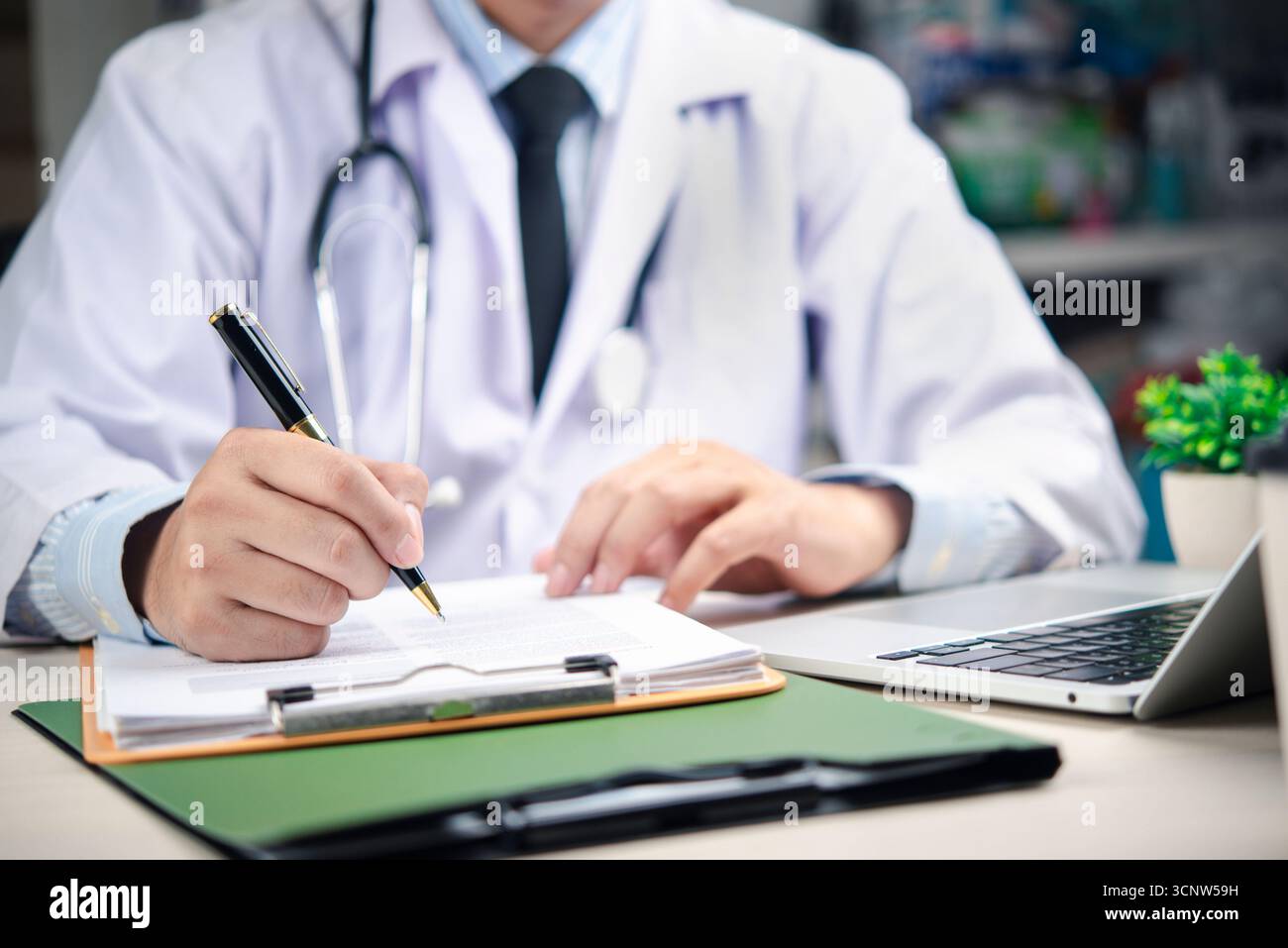 doctor writing on medical documents with a pen, reviewing patient ...