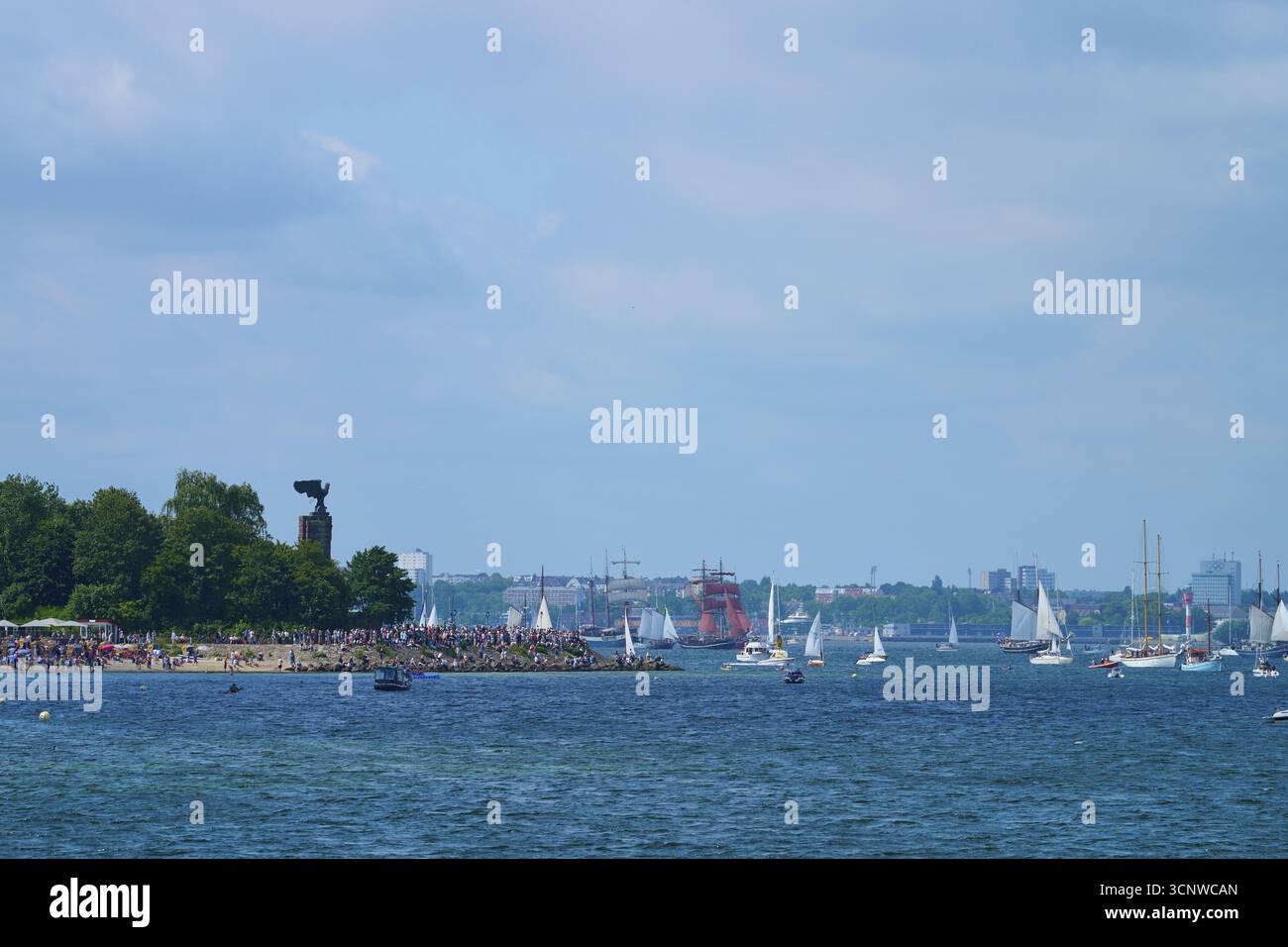 Boats and yacht on the sea near a tree-covered shore with people ...