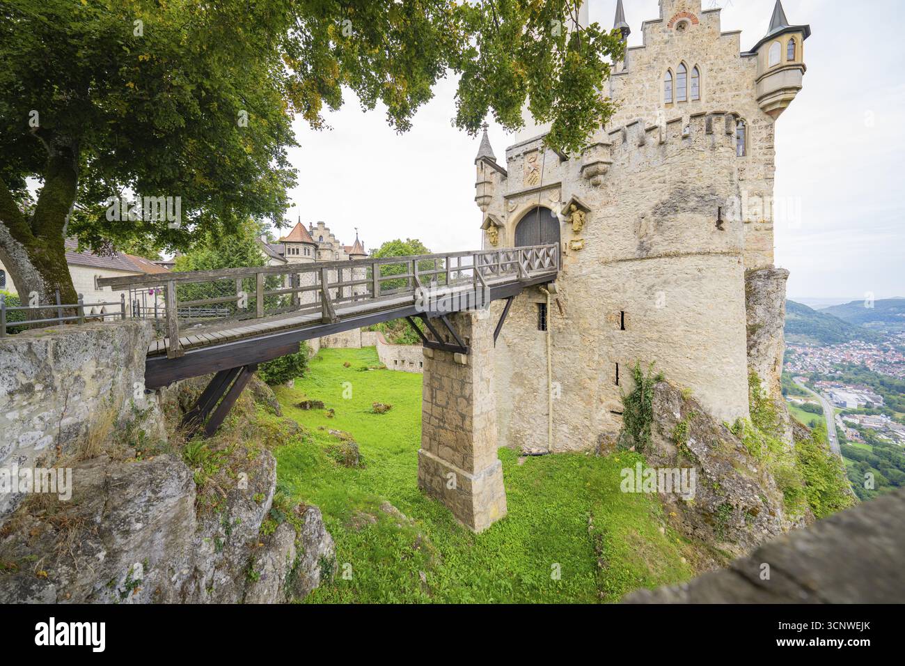 An impressive medieval castle on a rock with a wooden bridge over a ...