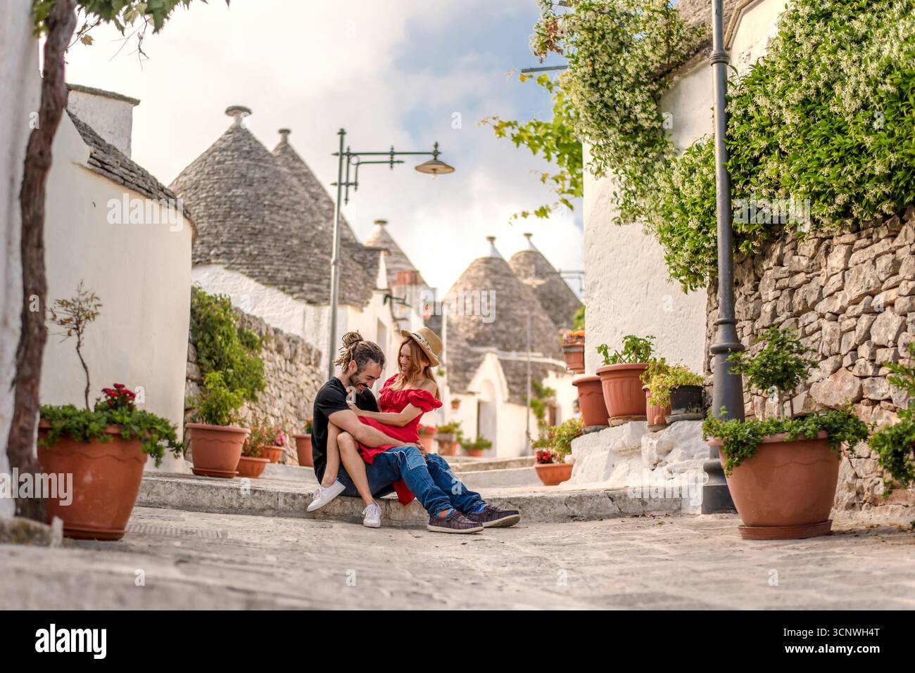 A couple enjoys a romantic moment in Alberobello, Puglia, Italy. They ...