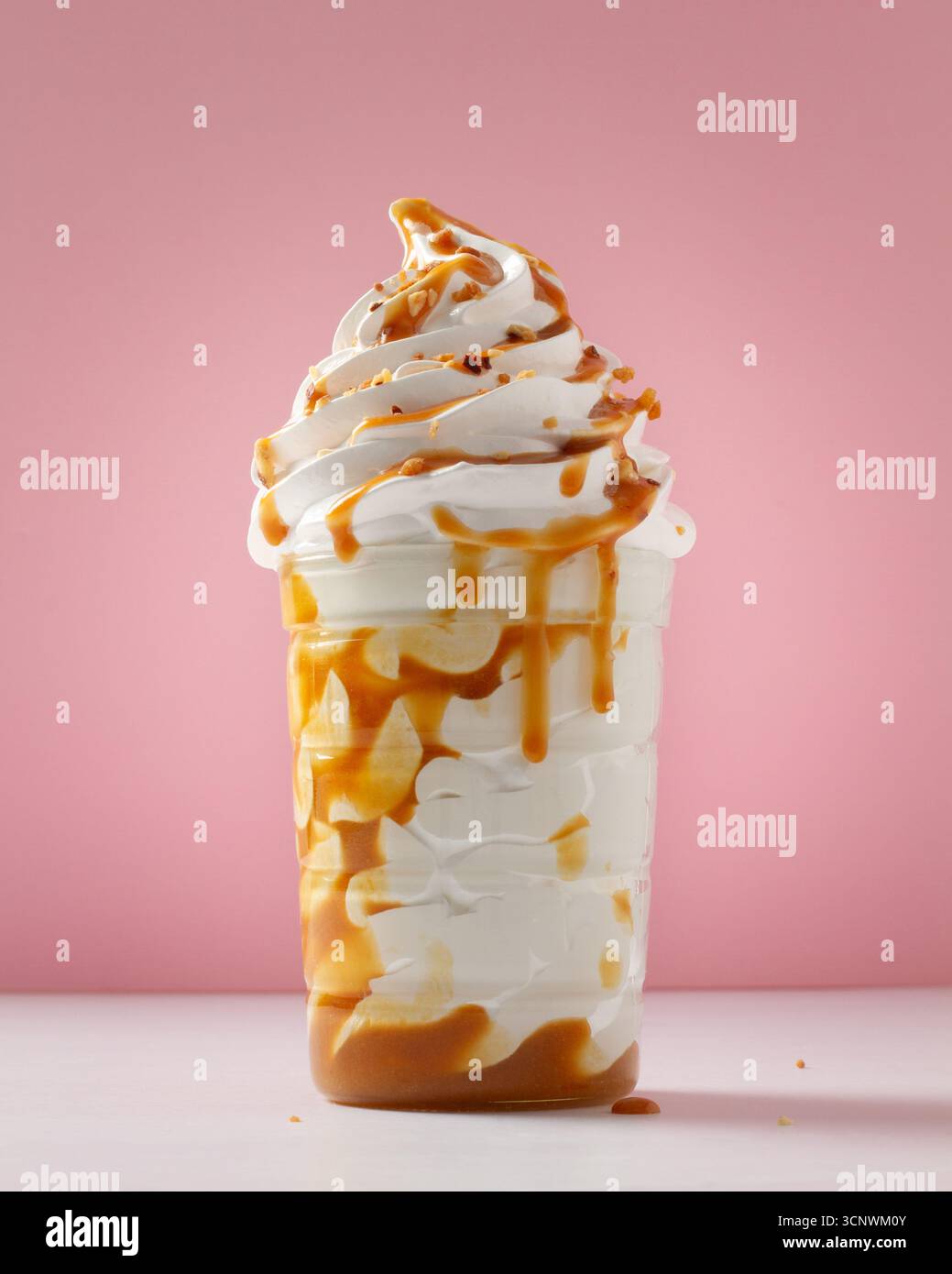 A tall swirl of creamy vanilla ice cream in a cup, drizzled with rich ...