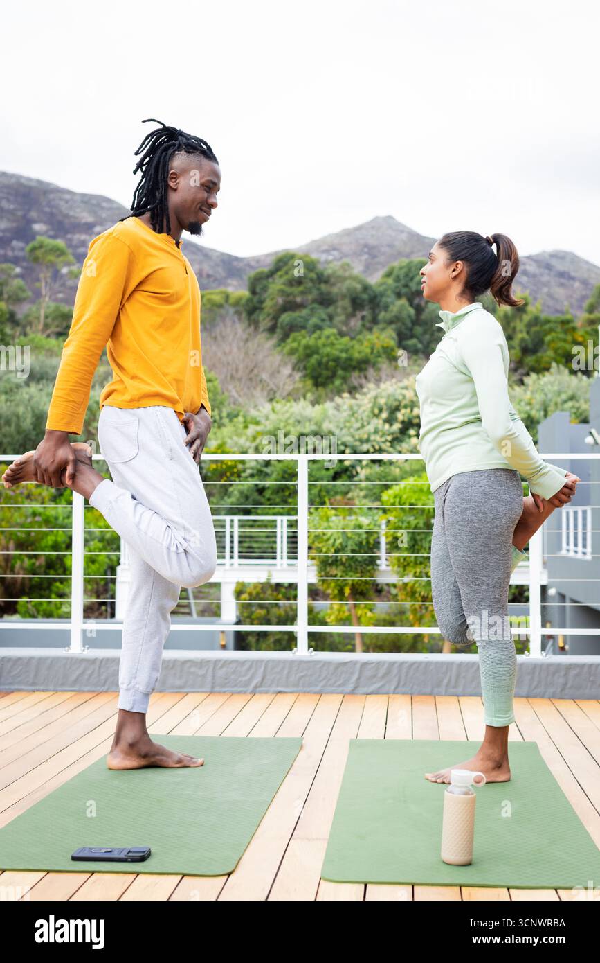 Diverse workout partners in sportswear stretching quadriceps on mats ...