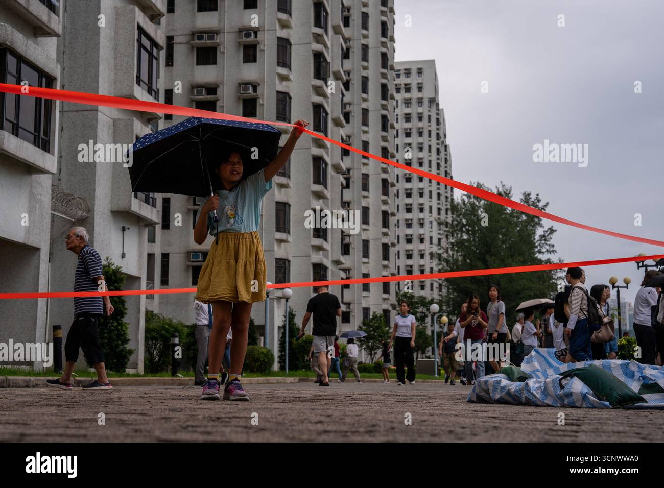A girl holding up warning tapes at Heng Fa Chuen as Typhoon Ragasa ...