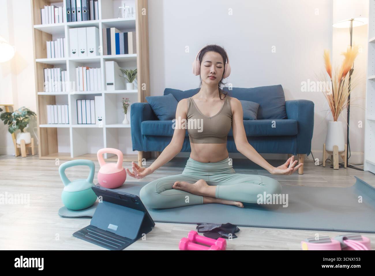 A young woman practices yoga at home, stretching gracefully on a mat ...
